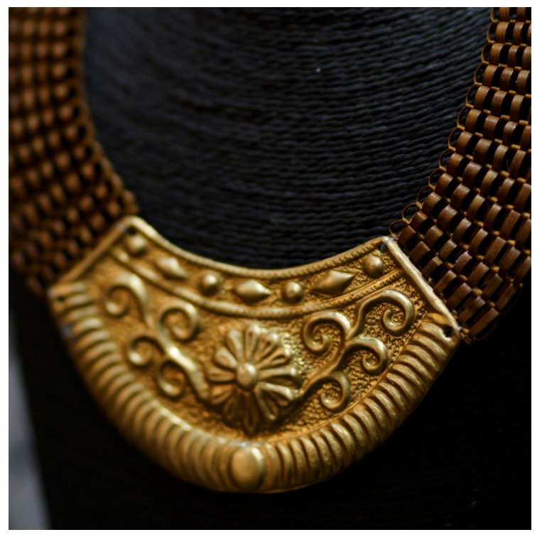 A gold-plated pendant set against agsam fern weavings