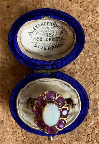 A gold ring with surrounding rubies and a central opal | The Thimble ...