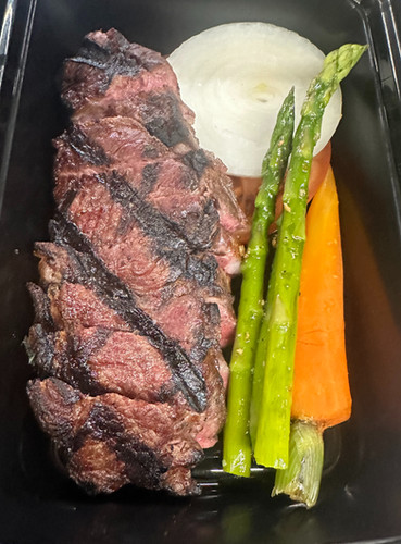 Grass fed sliced shell steak w/ tomato and onion served with root ...